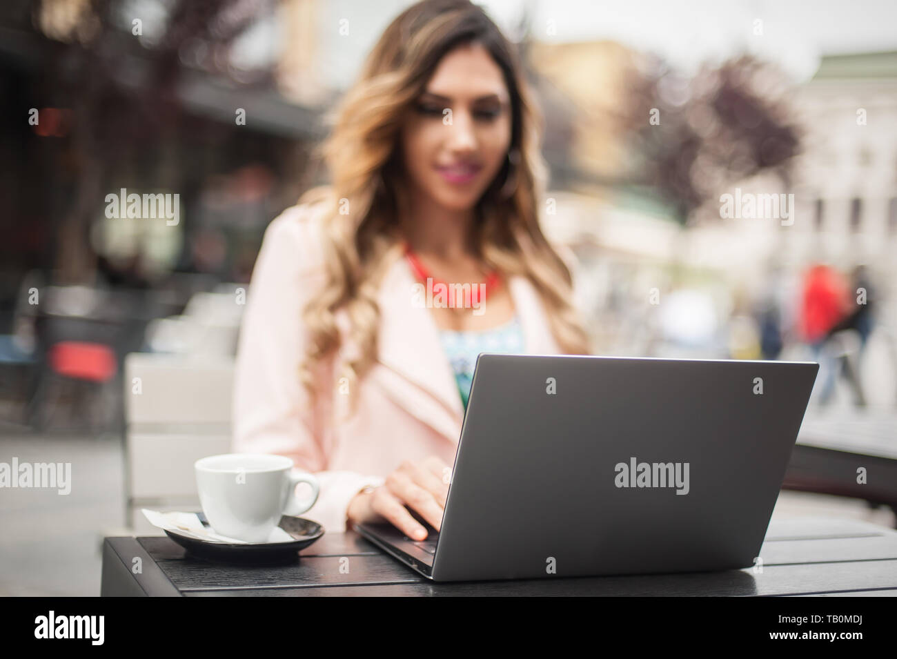 Young woman blogger freelancer in outdoor cafe with computer laptop ...
