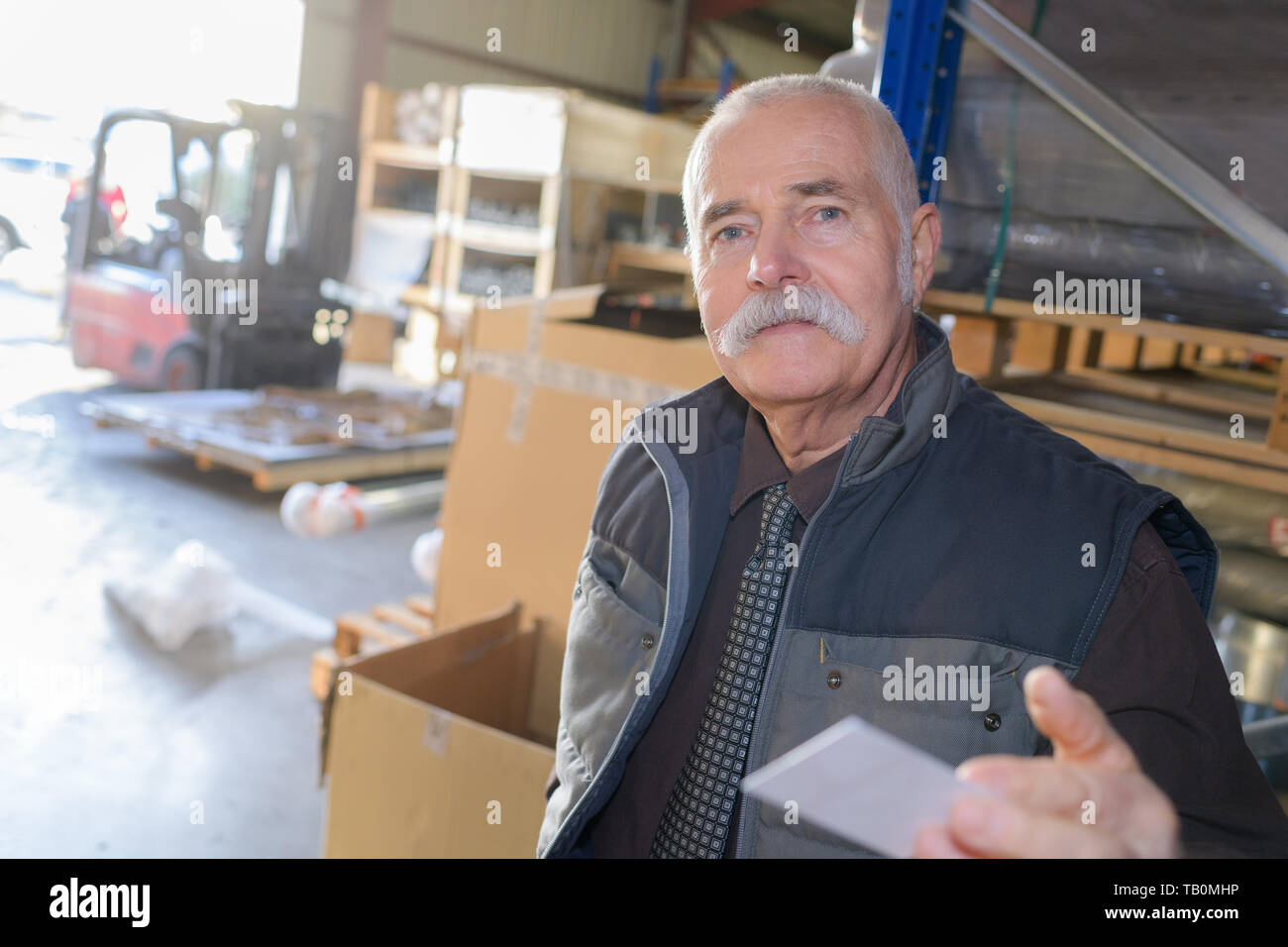 worker in uniform giving business-card in warehouse Stock Photo - Alamy