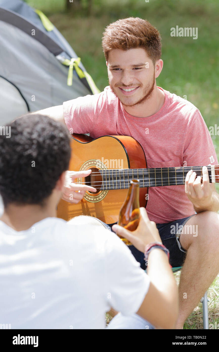 young men drinking beer and playing guitar on camping holiday Stock ...