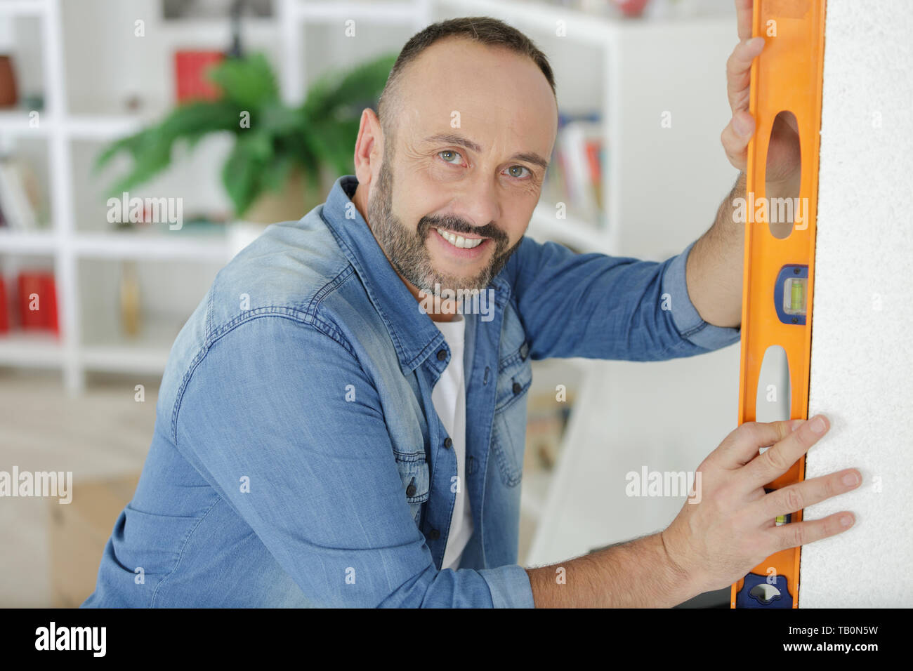 portrait of man using a spirit level in the home Stock Photo - Alamy
