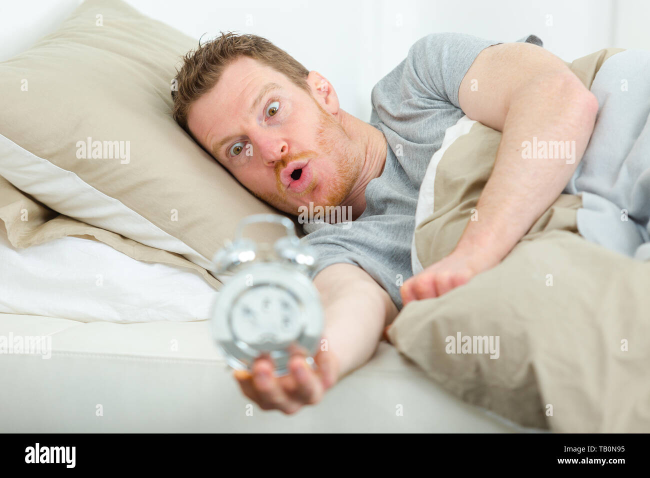 young stressed man is waking up and is shoked Stock Photo - Alamy