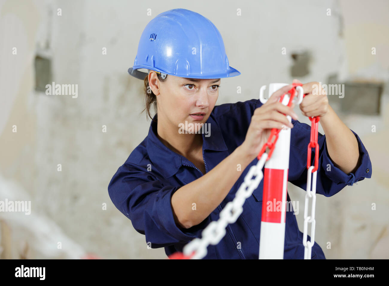 female builder putting up safety barrier around work site Stock Photo ...