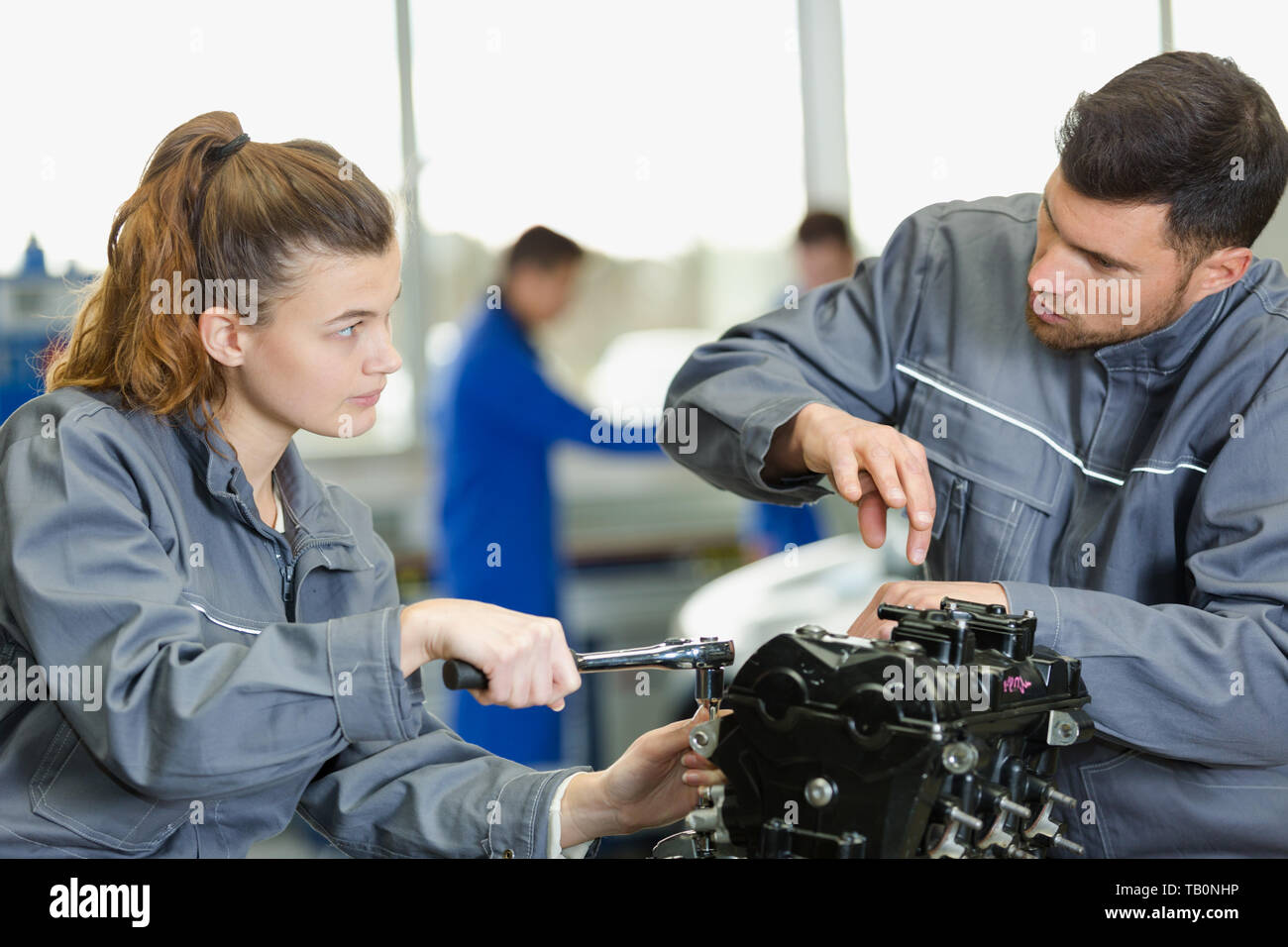 two mechanics operating wheel equilibrium control machinery at auto ...