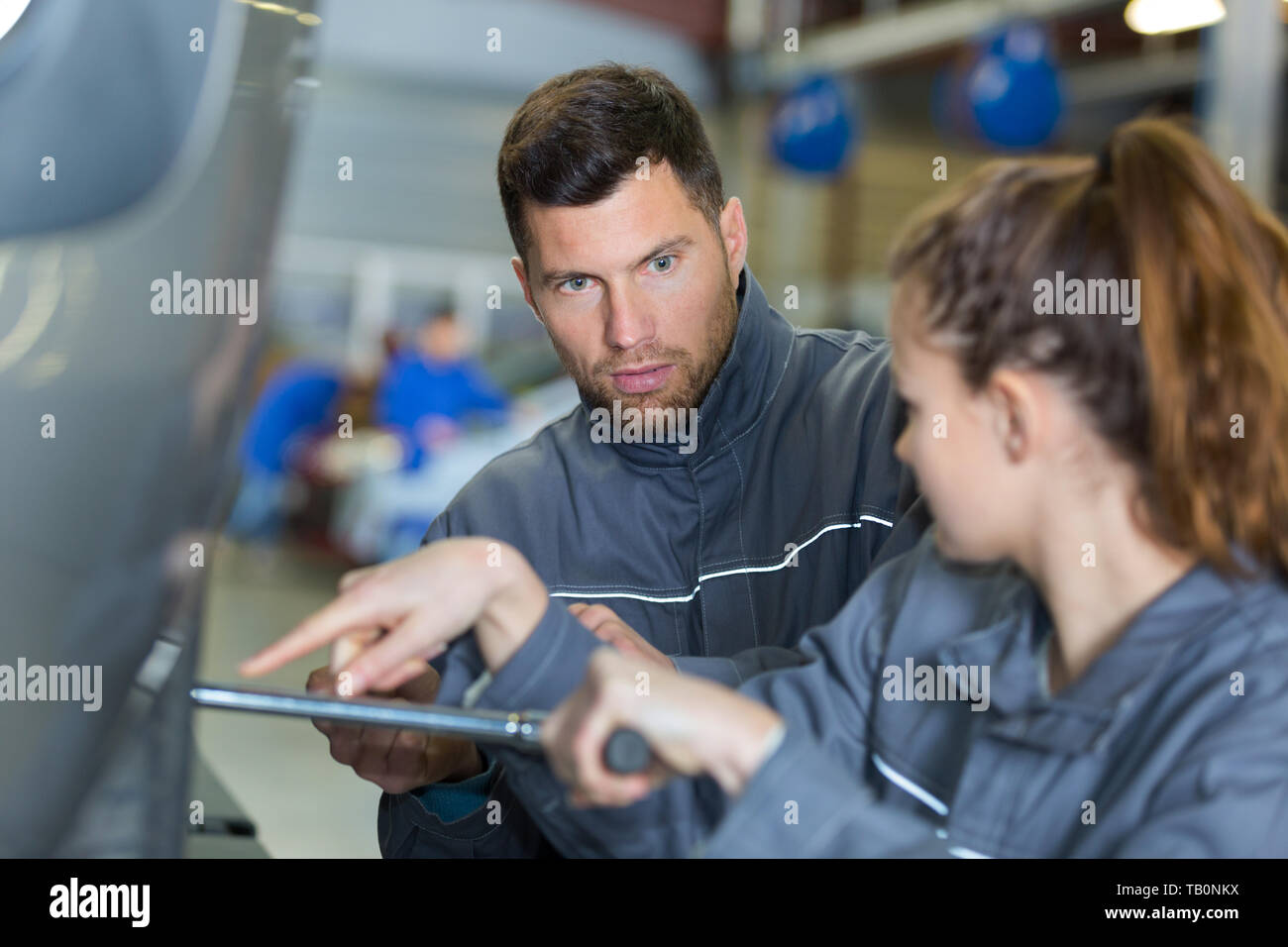 mechanic advising female apprentice tightening wheel nuts Stock Photo ...
