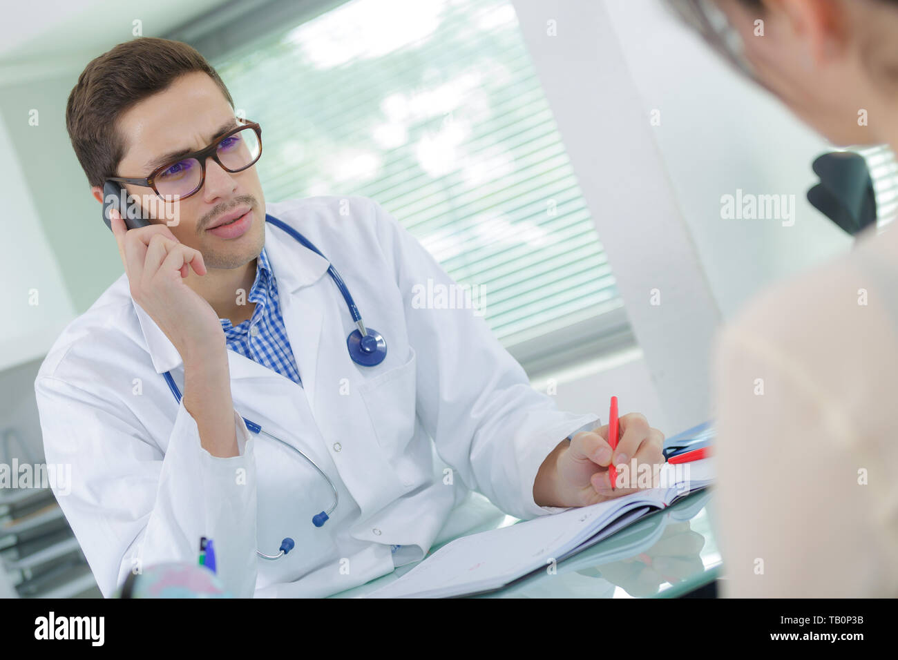 doctor using telephone while in consultation with patient Stock Photo ...