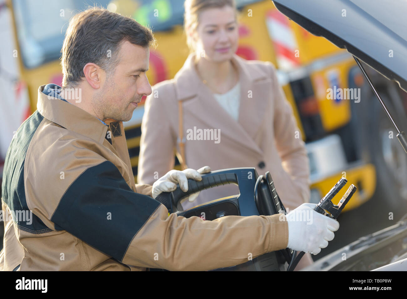 male worker helping female with broken car Stock Photo - Alamy
