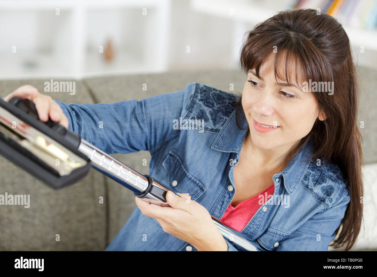 busy woman cleaning sofa with vacuum cleaner Stock Photo - Alamy