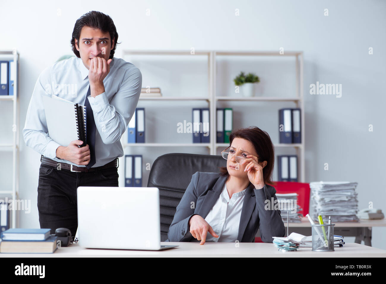 Old female boss and young male employee in the office Stock Photo - Alamy