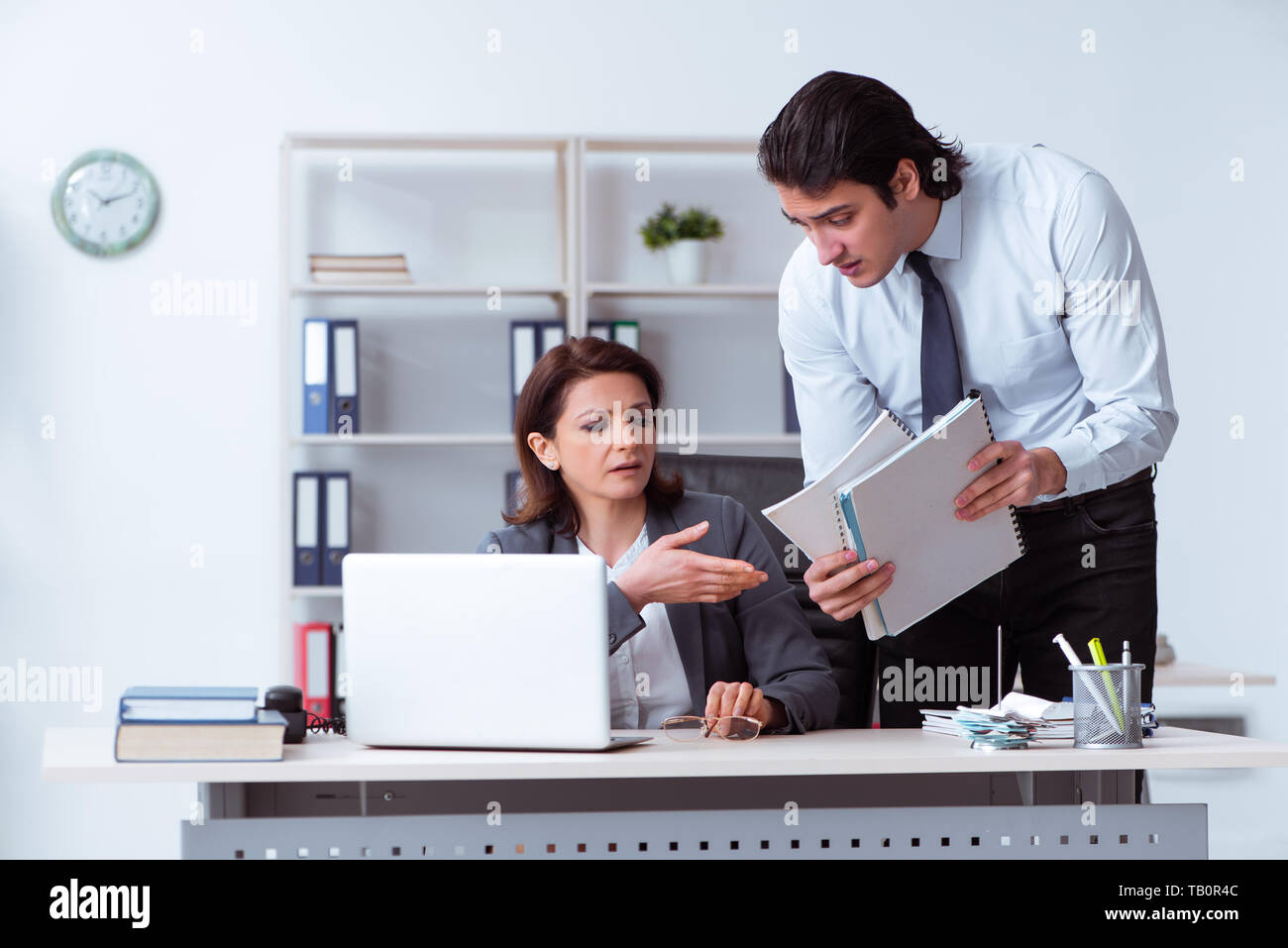 Old female boss and young male employee in the office Stock Photo - Alamy
