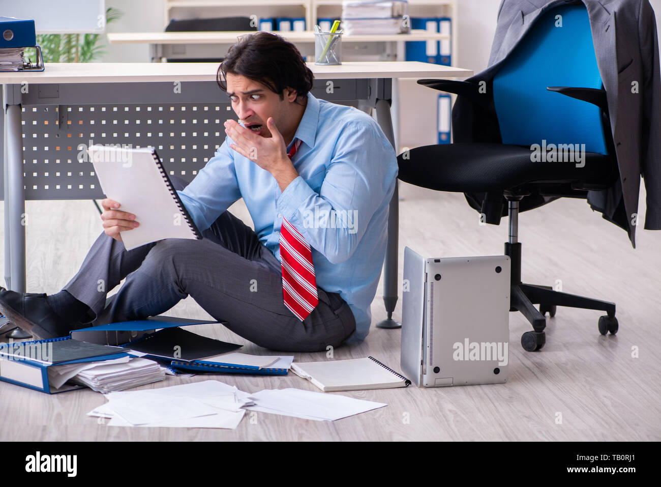 The young male employee unhappy with excessive work Stock Photo - Alamy