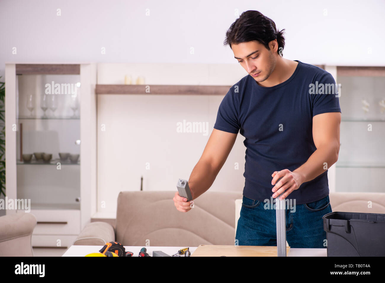 Young man repairing furniture at home Stock Photo - Alamy