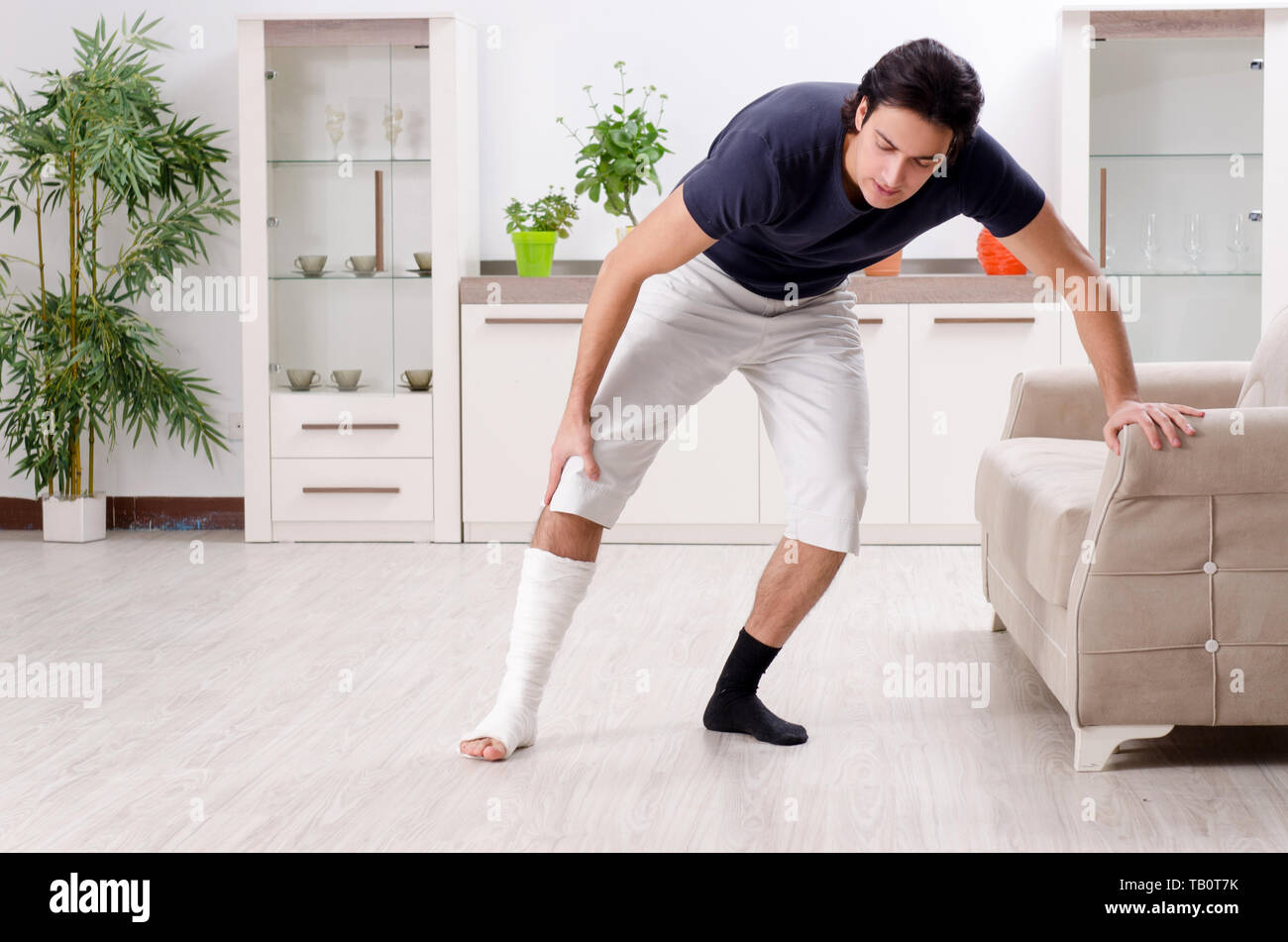 Leg injured young man suffering at home Stock Photo - Alamy