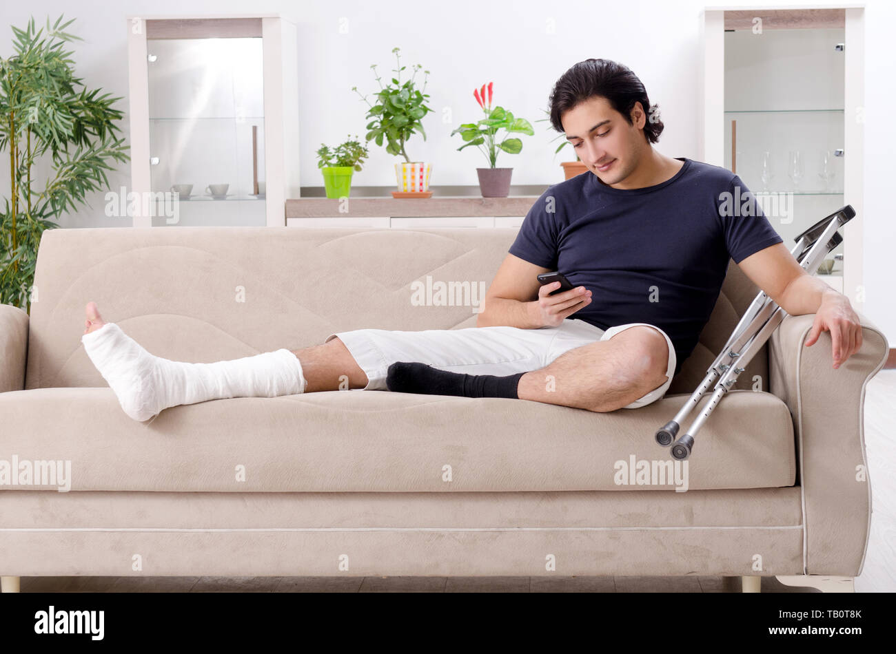 Leg injured young man suffering at home Stock Photo - Alamy