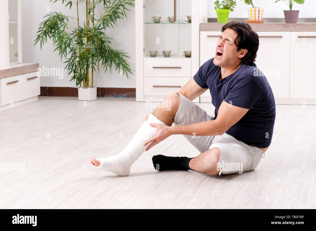 Leg injured young man suffering at home Stock Photo - Alamy