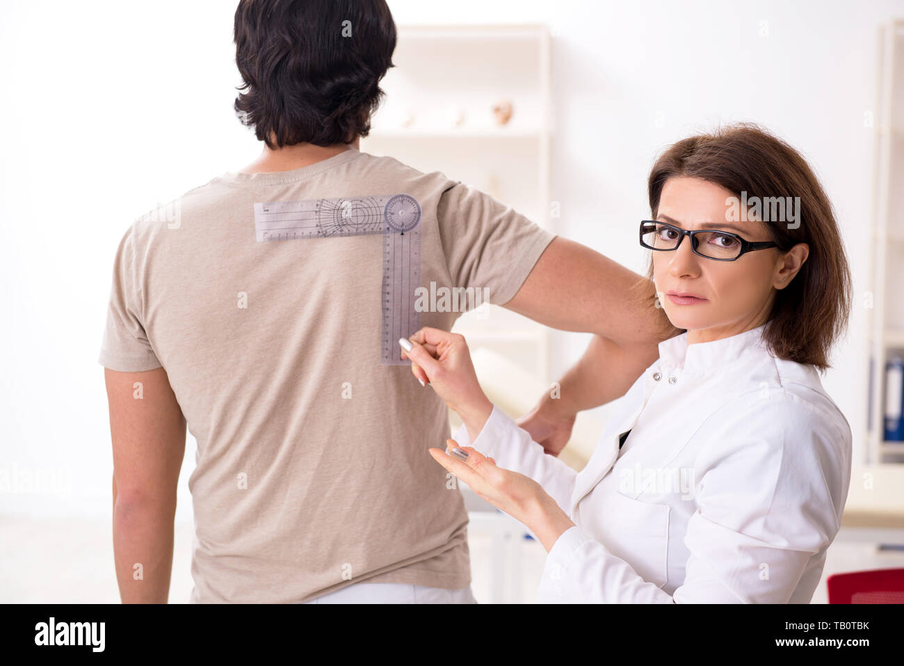 Female doctor checking patient's joint flexibility with goniometer ...