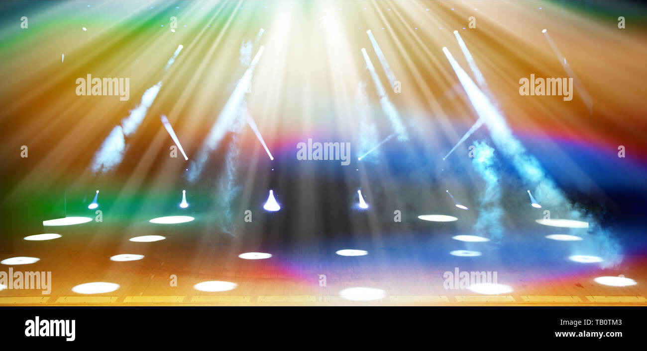 Illuminated free concert stage with haze and rays of multicolored light ...