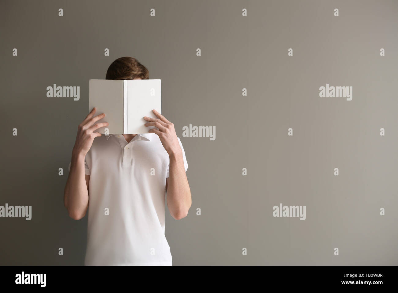 Young man with book covering his face hi-res stock photography and ...