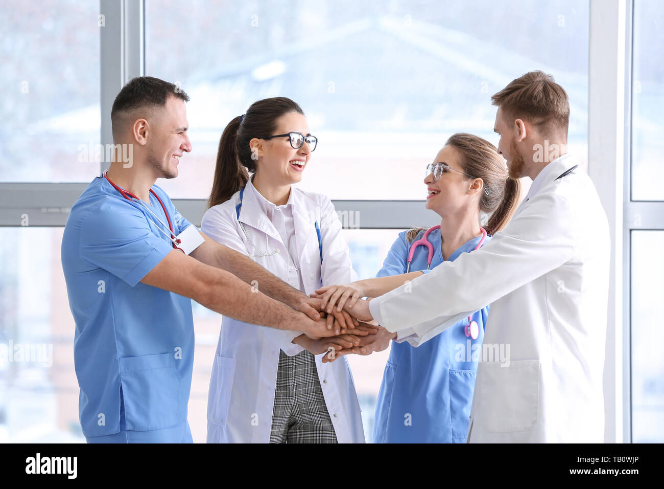 Team of doctors putting hands together in clinic Stock Photo - Alamy