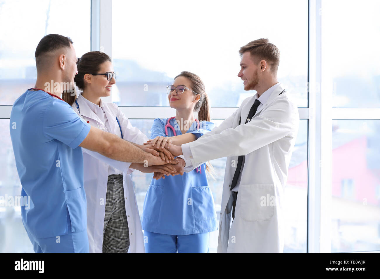 Team of doctors putting hands together in clinic Stock Photo - Alamy