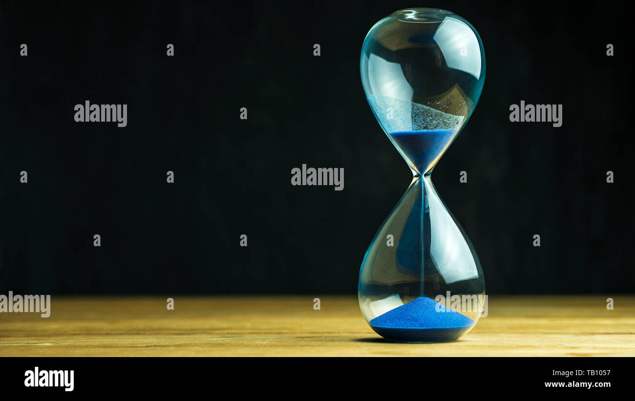 Sand clock on wooden table and black background. Copy space for your ...