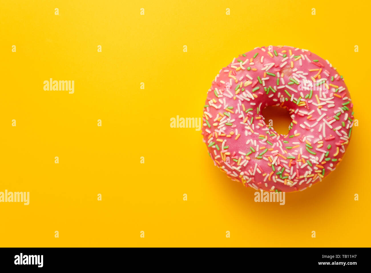 pink donut on yellow background top view Stock Photo - Alamy