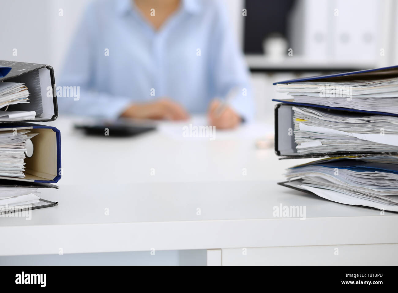 Binders with papers are waiting to be processed by business woman or ...