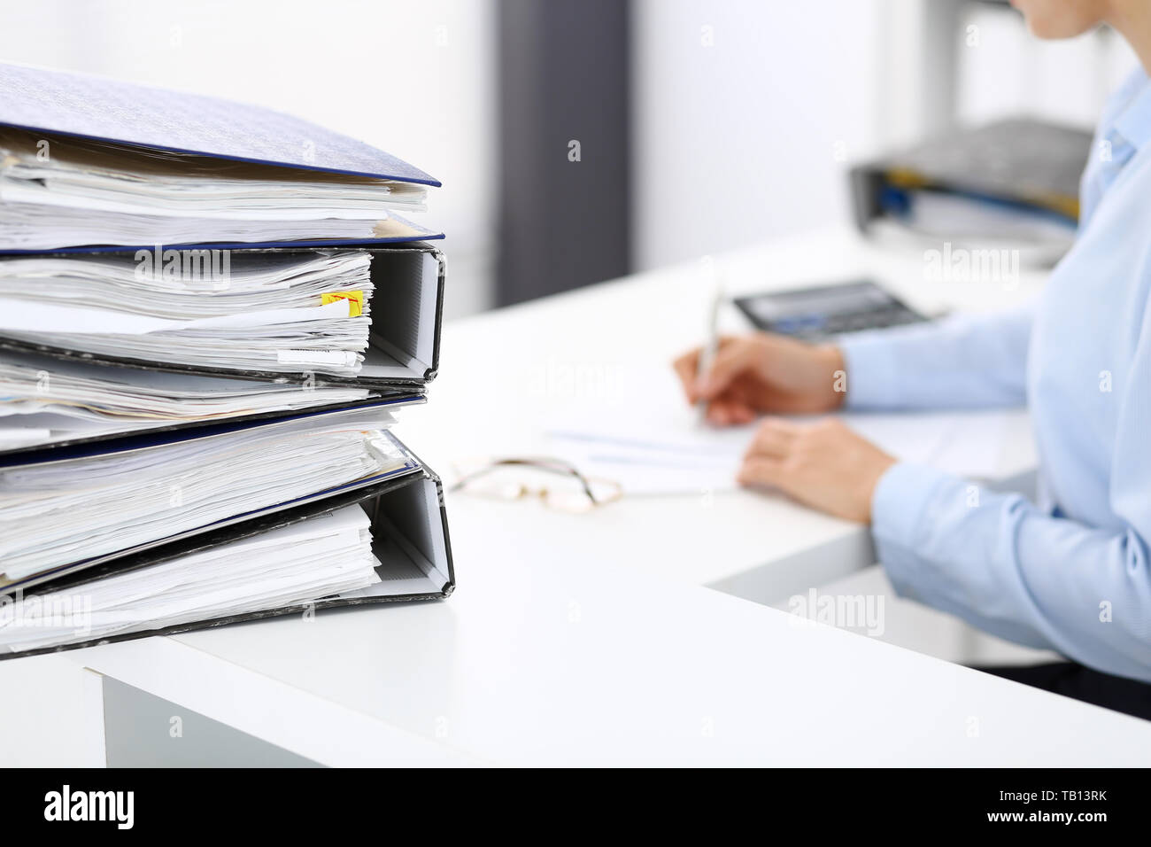 Binders with papers are waiting to be processed by business woman or ...