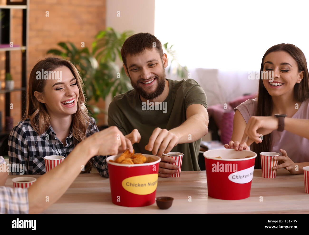 Group of friends eating nuggets at home Stock Photo - Alamy