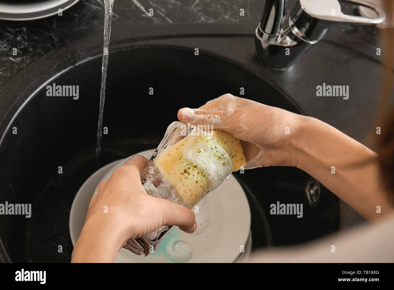 Woman washing glass in kitchen sink Stock Photo - Alamy
