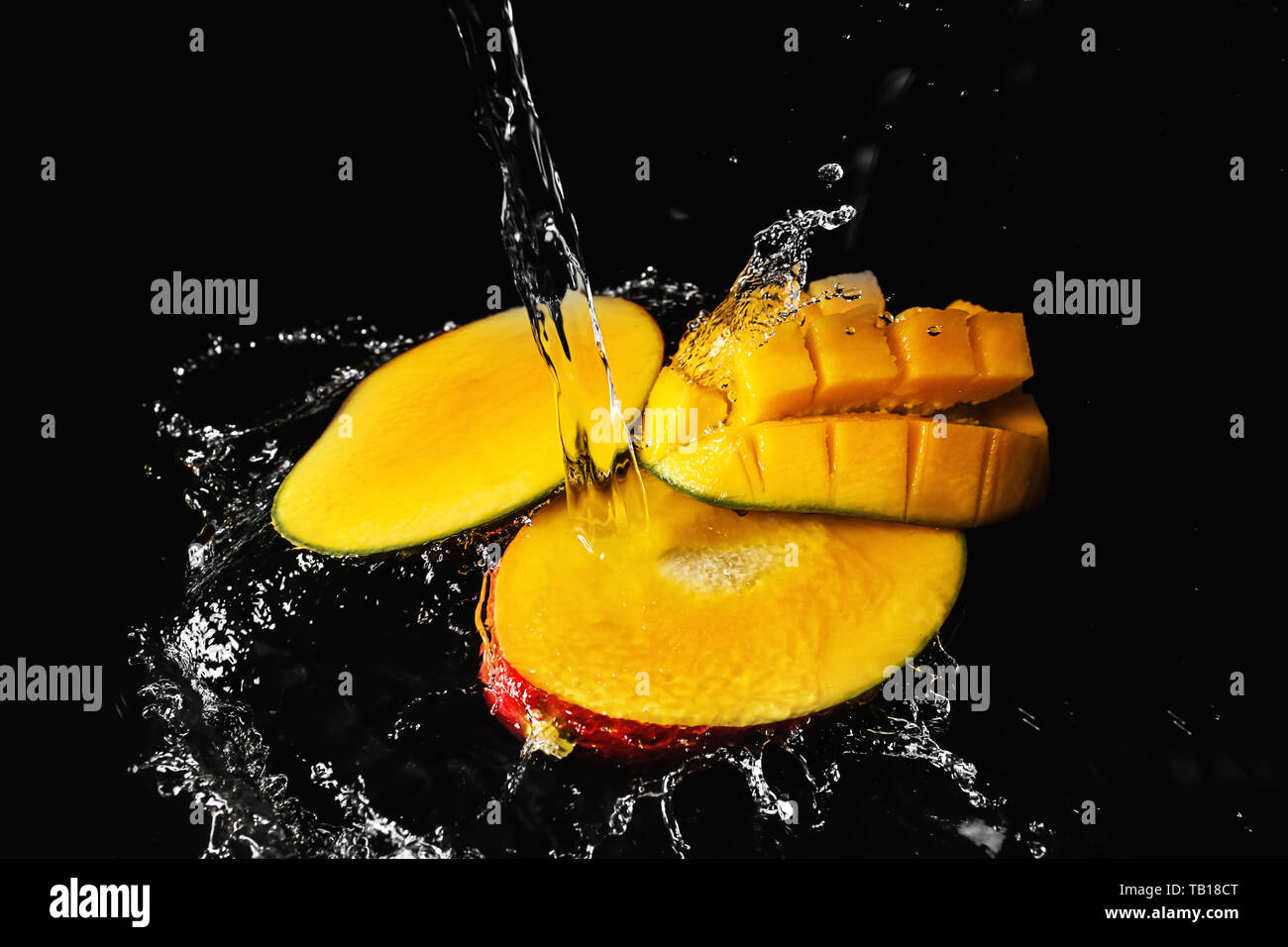Ripe cut mango with water splash on dark background Stock Photo - Alamy