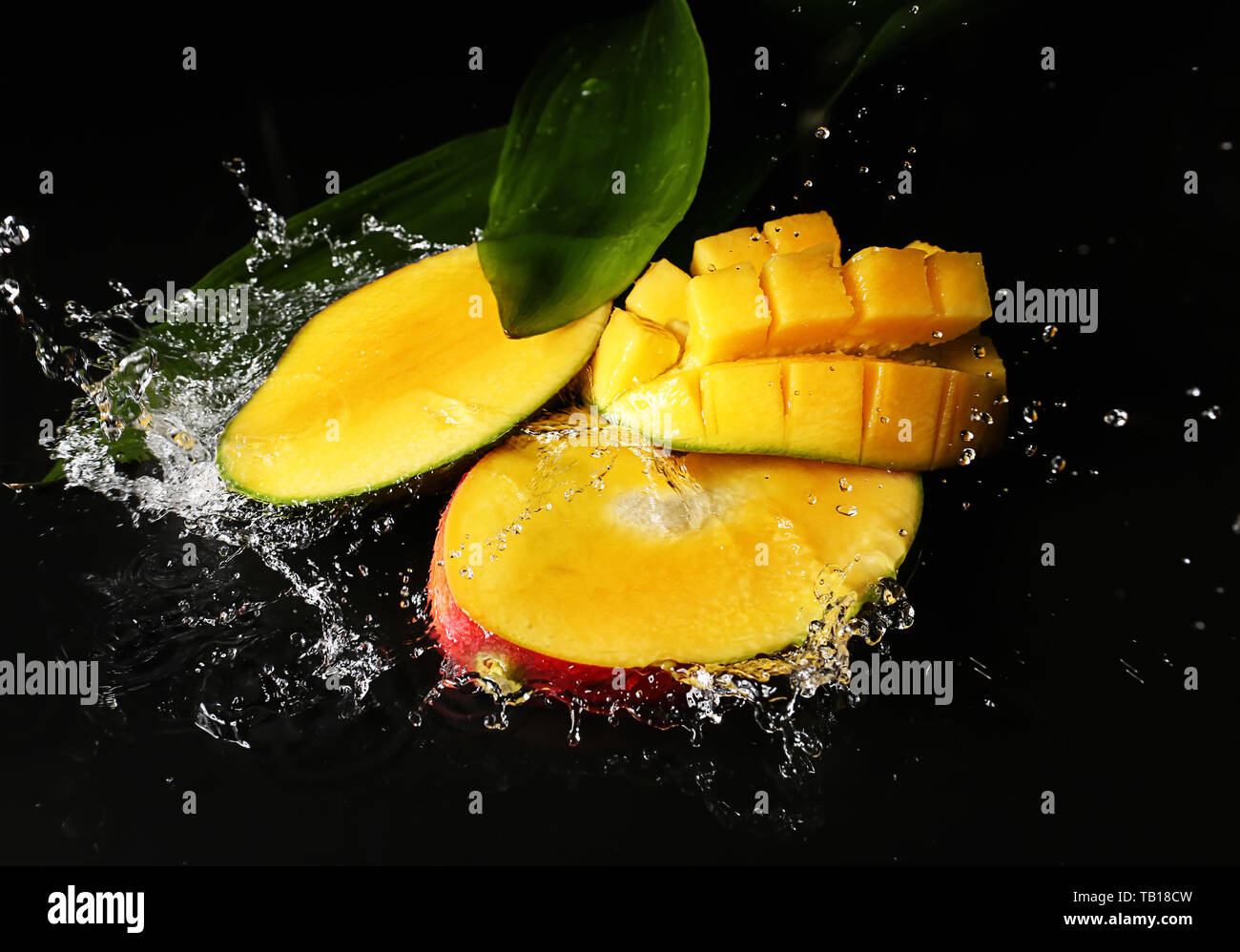 Ripe cut mango with water splash on dark background Stock Photo - Alamy