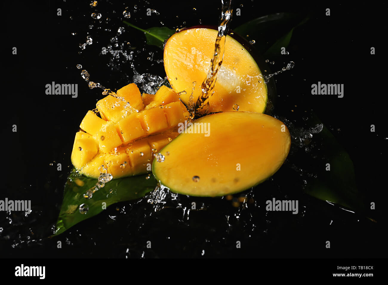 Ripe cut mango with water splash on dark background Stock Photo - Alamy
