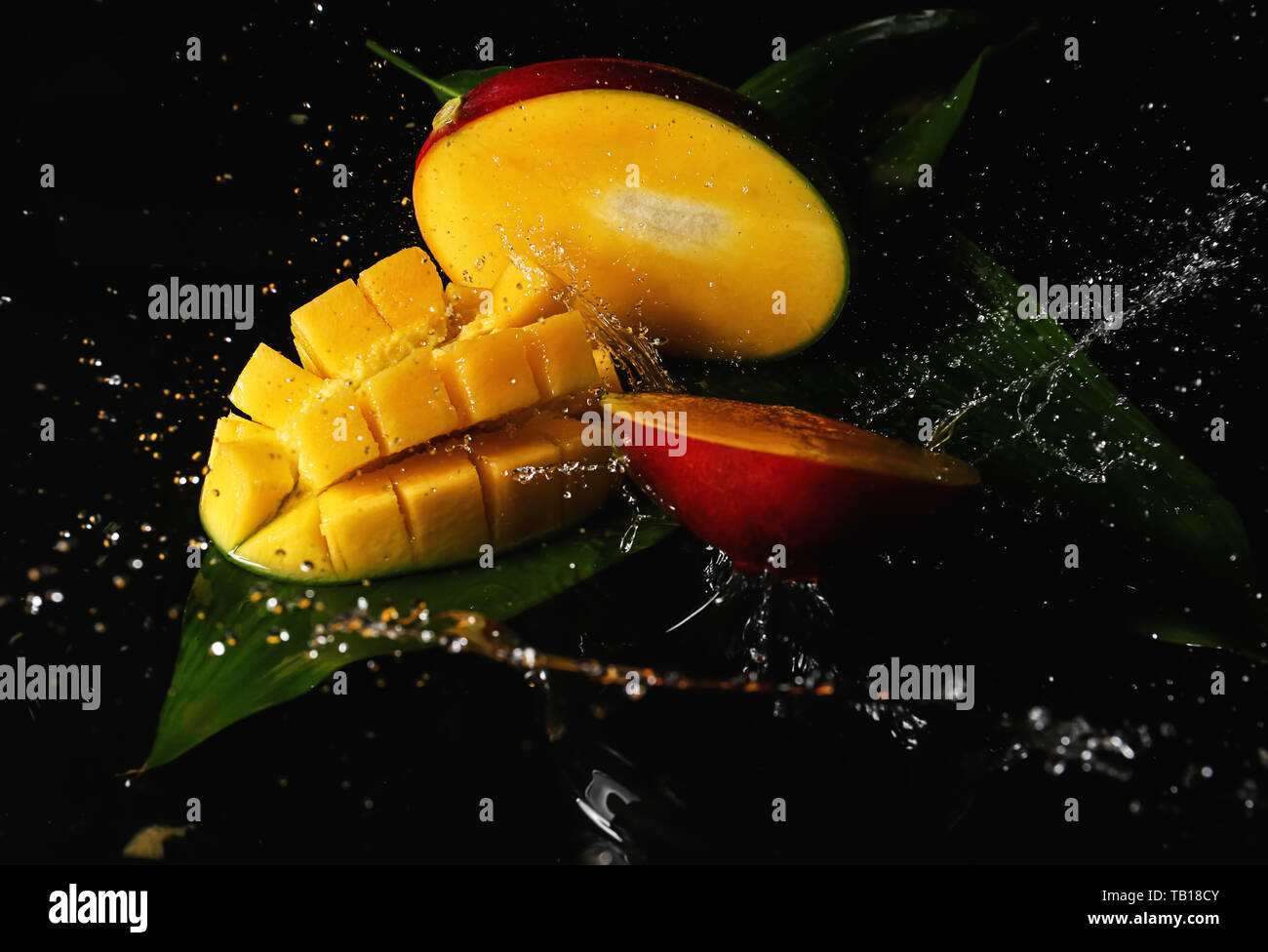 Ripe cut mango with water splash on dark background Stock Photo - Alamy