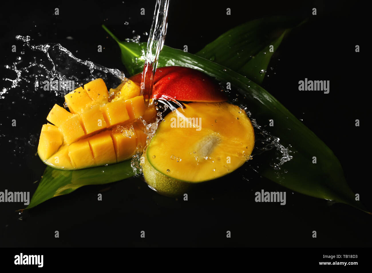 Ripe cut mango with water splash on dark background Stock Photo - Alamy