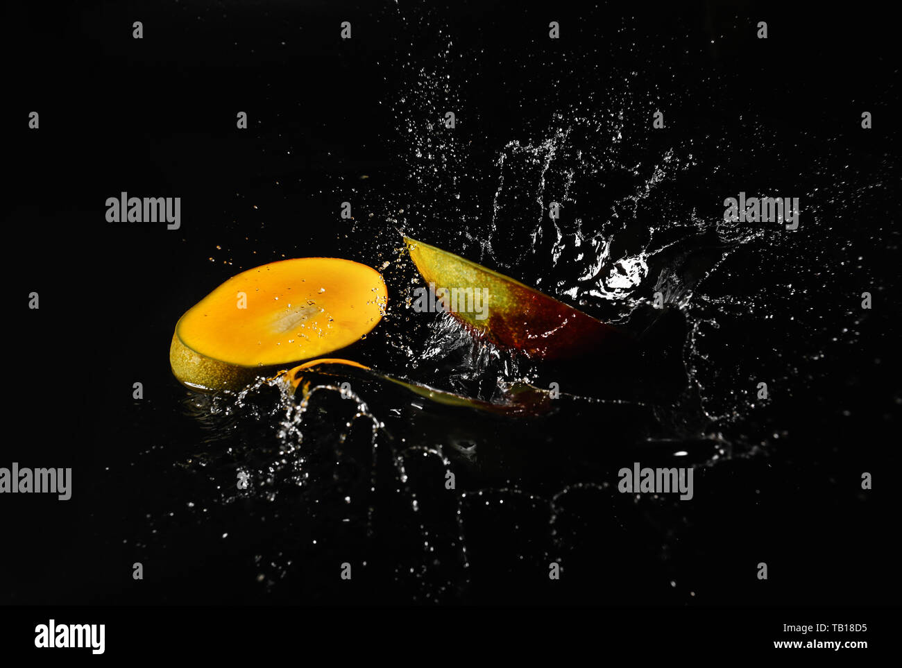 Ripe cut mango with water splash on dark background Stock Photo - Alamy