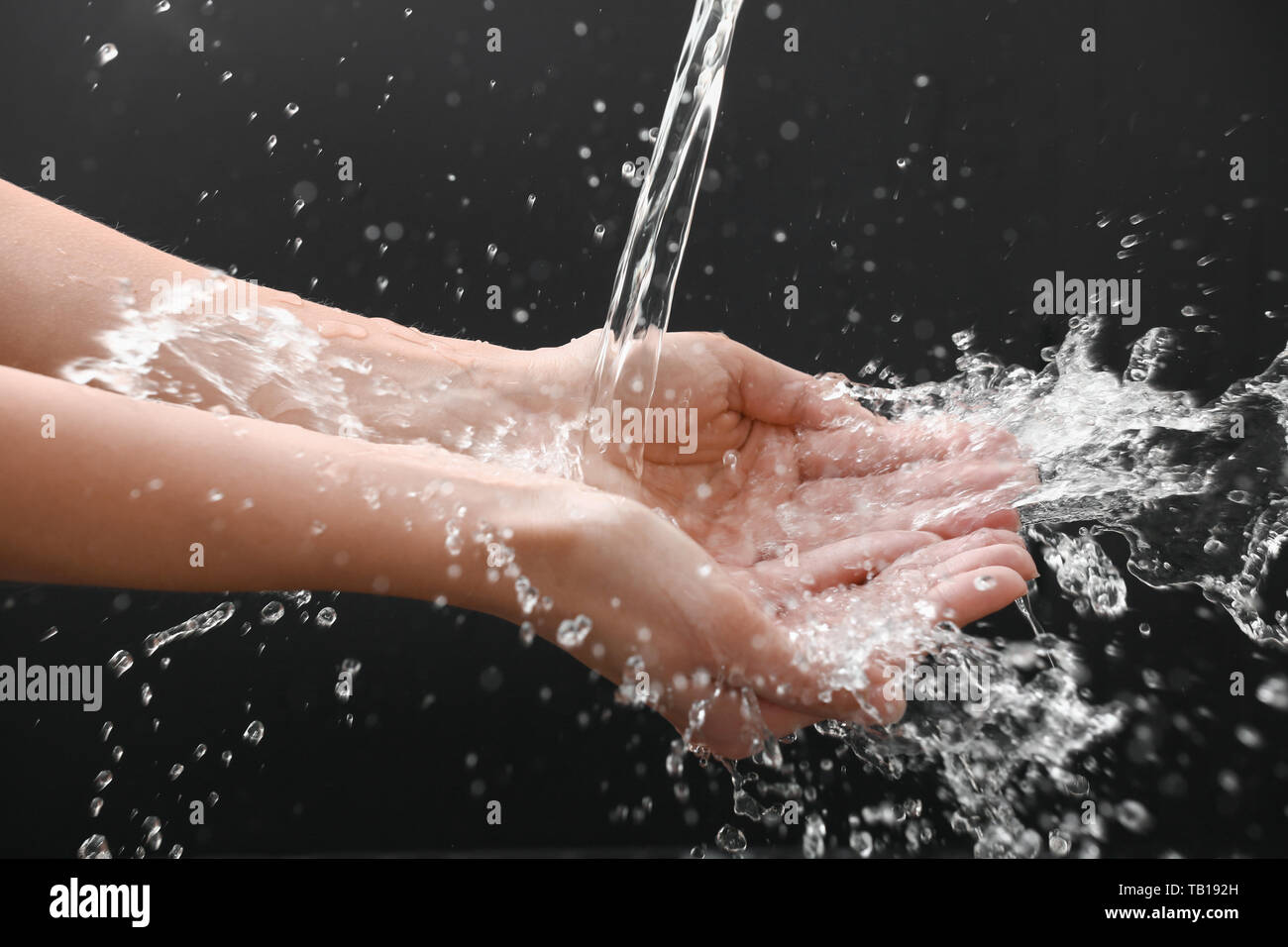 Woman washing hands on dark background Stock Photo - Alamy