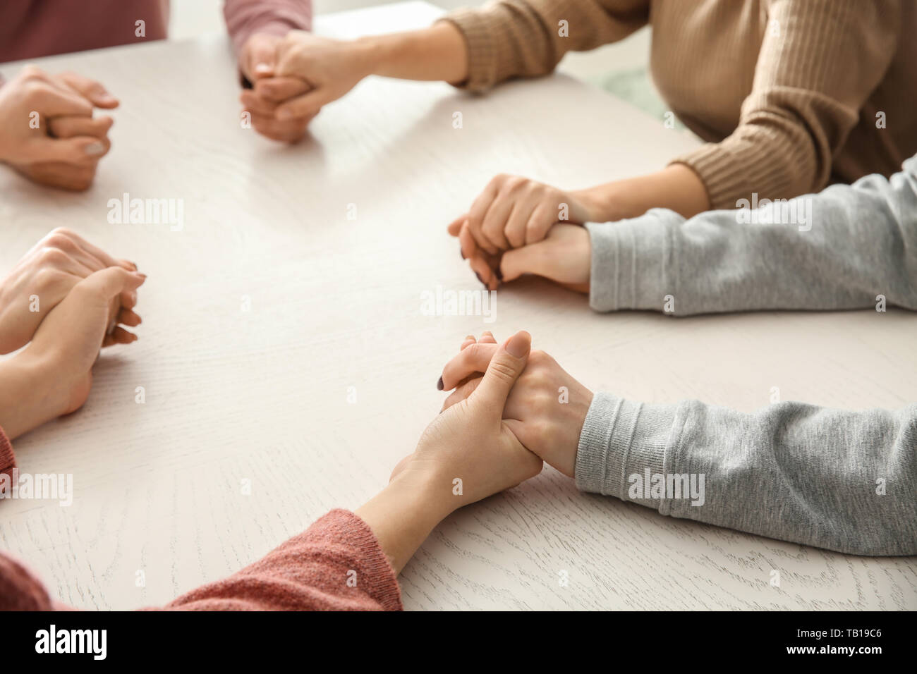 Group of people praying together at table Stock Photo - Alamy