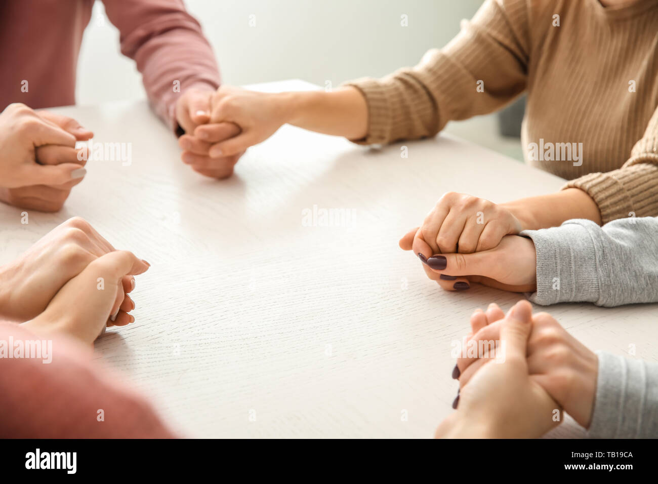 Group of people praying together at table Stock Photo - Alamy