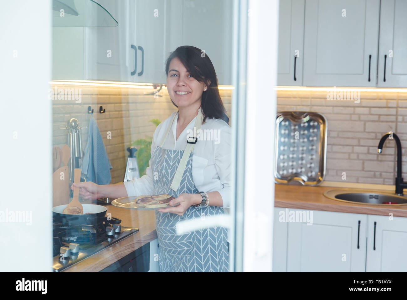 woman cooking pancakes view through window. glass Stock Photo - Alamy