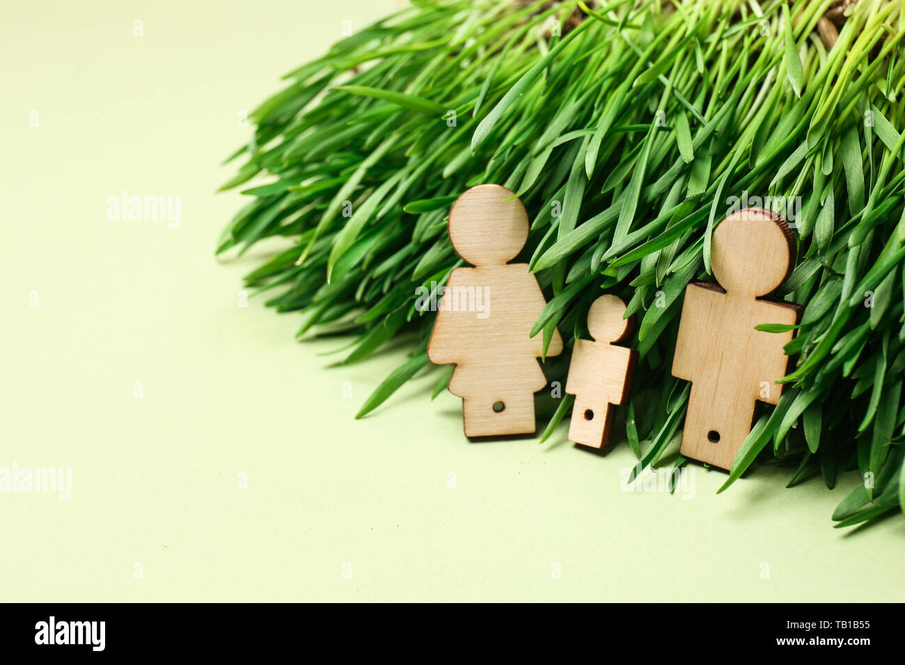 Wooden human figures with green grass on light background. Ecology ...