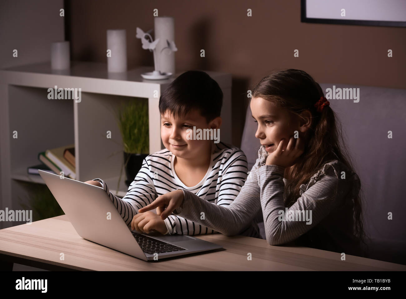 Cute little children with laptop watching cartoons late in evening ...