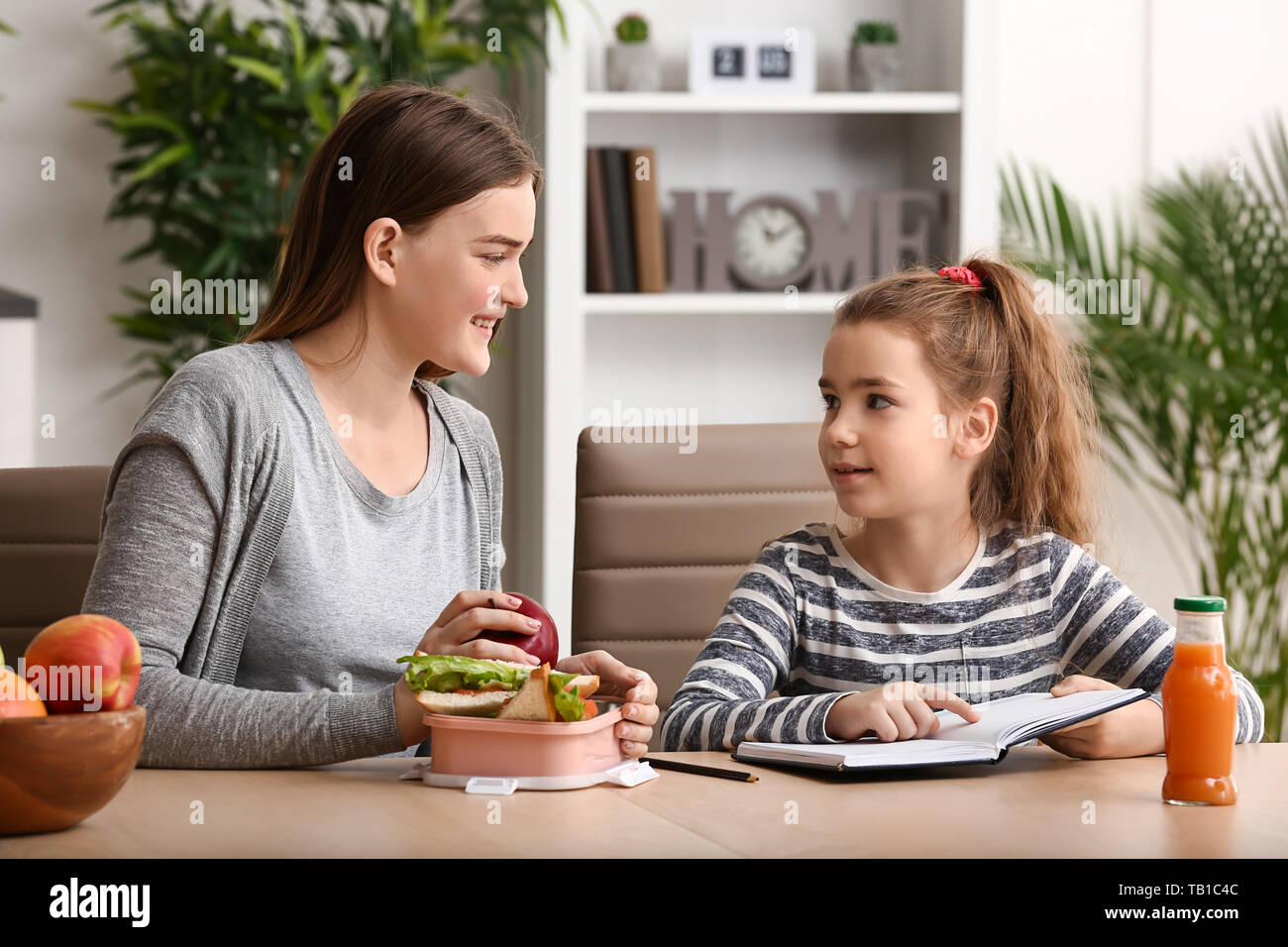 Mother packing school lunch for her little daughter at home Stock Photo ...
