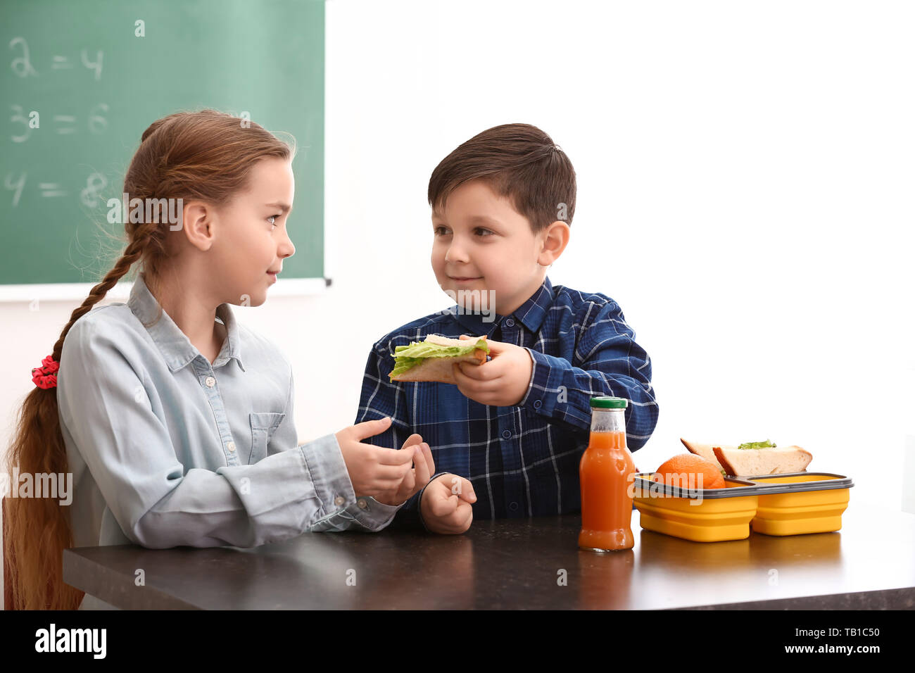Little boy sharing his school lunch with girl in classroom Stock Photo ...