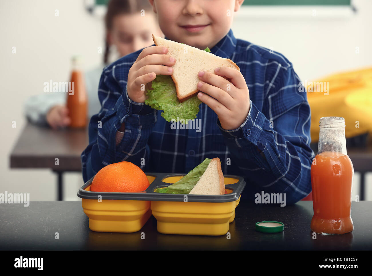 Little boy having school lunch in classroom Stock Photo - Alamy
