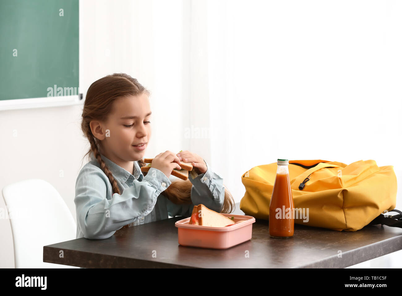 Little girl having school lunch in classroom Stock Photo - Alamy