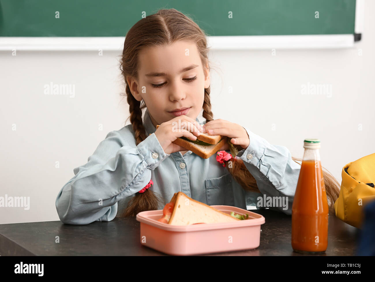 Little girl having school lunch in classroom Stock Photo - Alamy