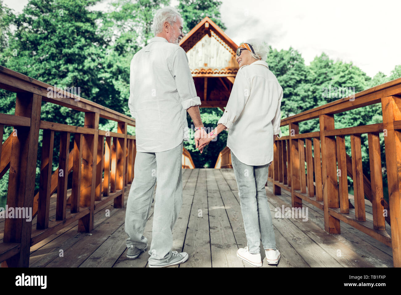 Happy couple holding hands and standing on the bridge Stock Photo - Alamy