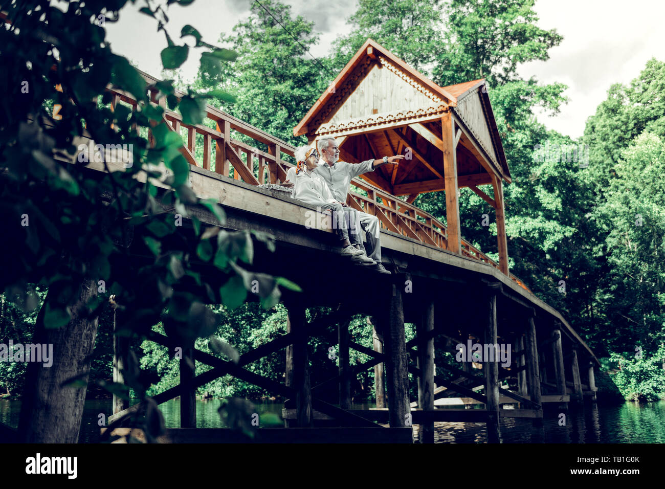 Beaming husband and wife sitting at bridge and enjoying nature Stock ...