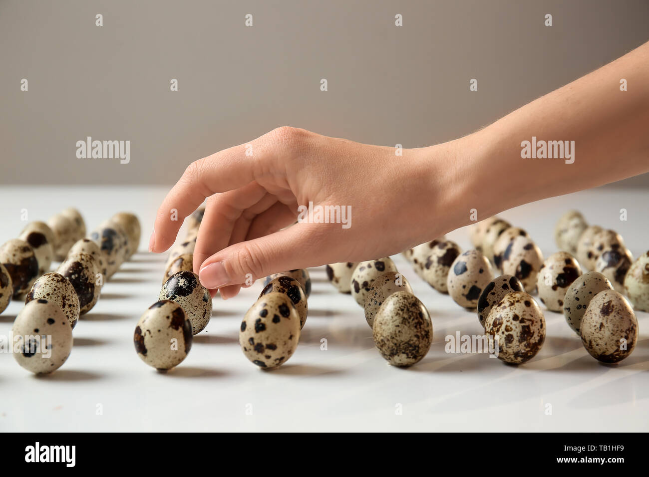 Female hand with raw quail eggs on white table Stock Photo - Alamy