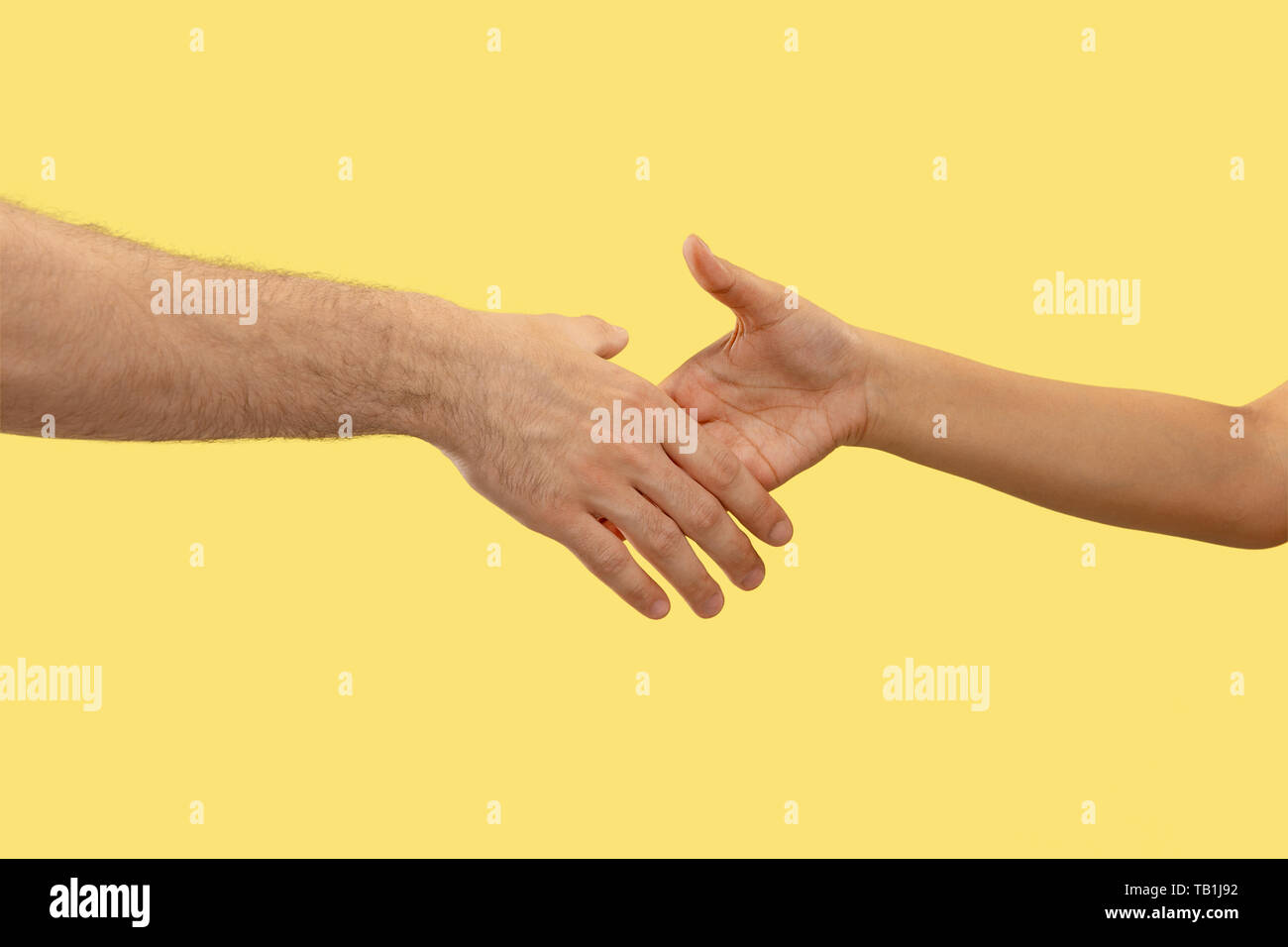Closeup shot of human holding hands isolated on yellow studio ...